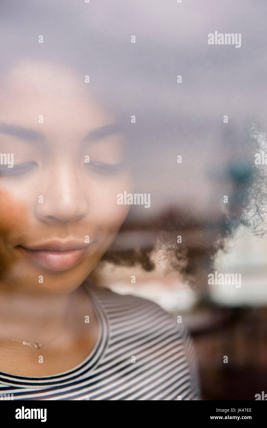 Pensive African American woman behind window Stock Photo - Alamy