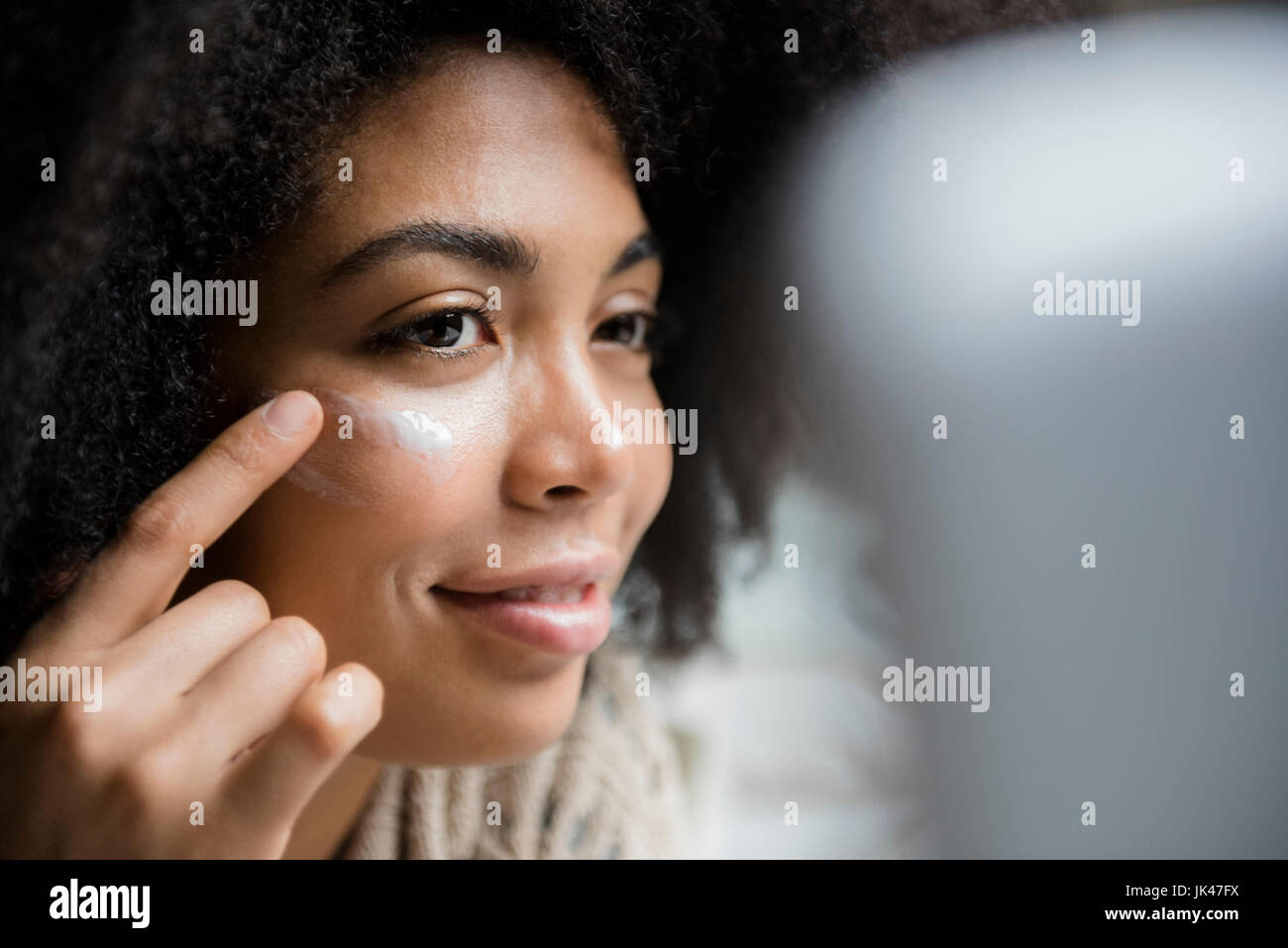 African American woman applying lotion to face Stock Photo - Alamy