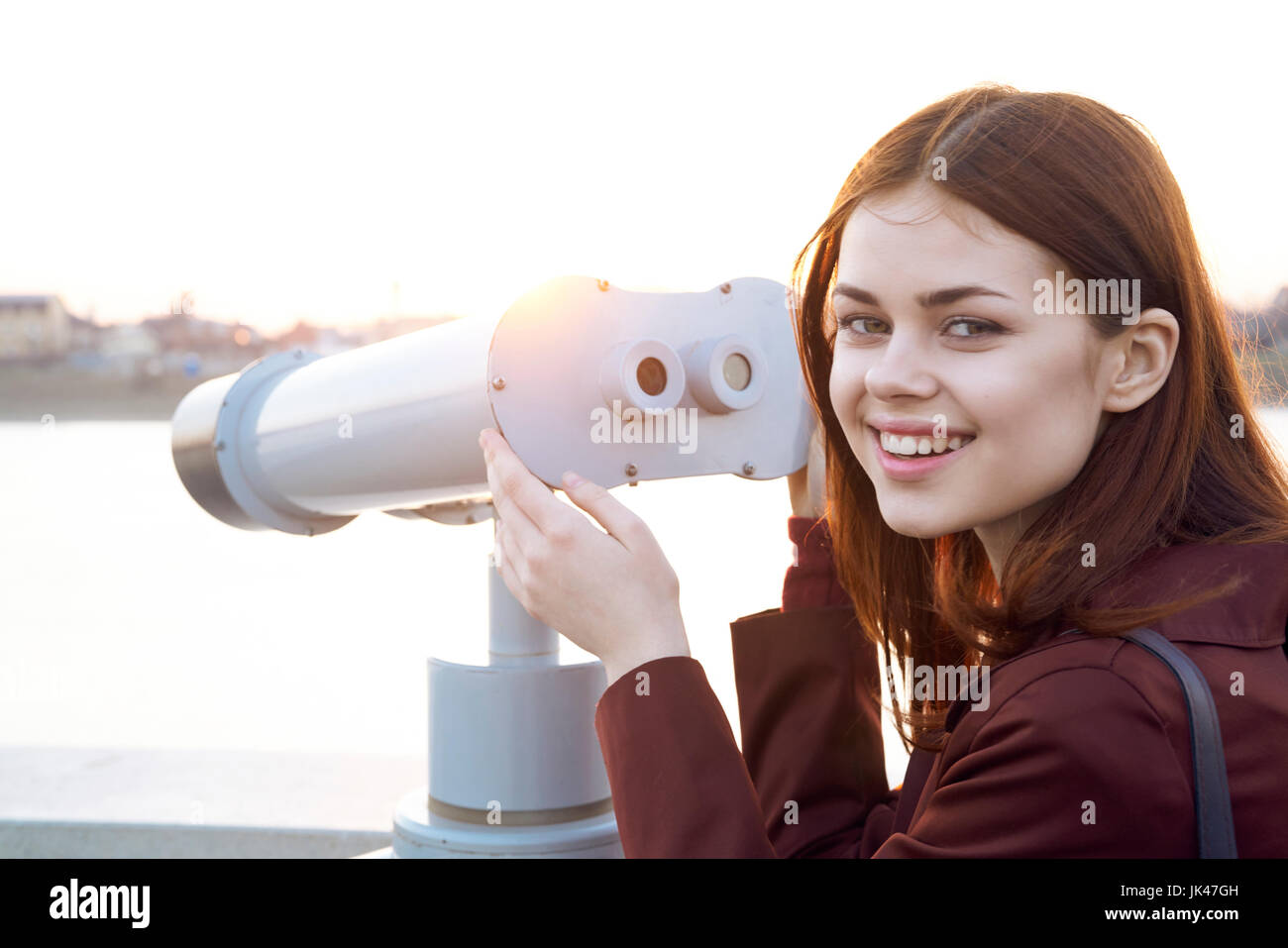 Smiling Caucasian woman using binoculars at waterfront Stock Photo - Alamy