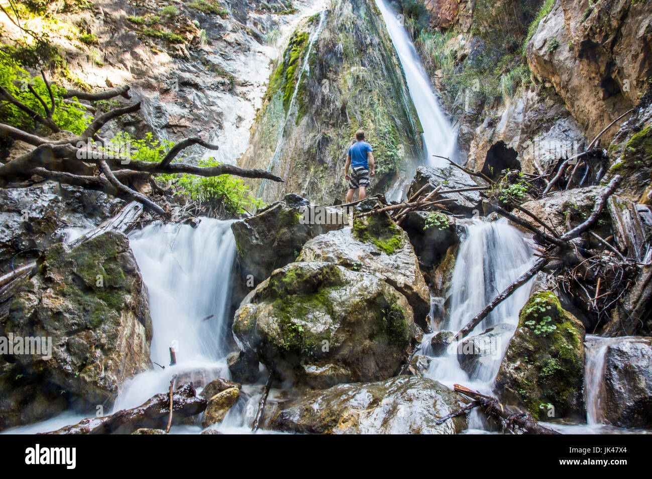 Caucasian man standing on rocks watching waterfall Stock Photo - Alamy