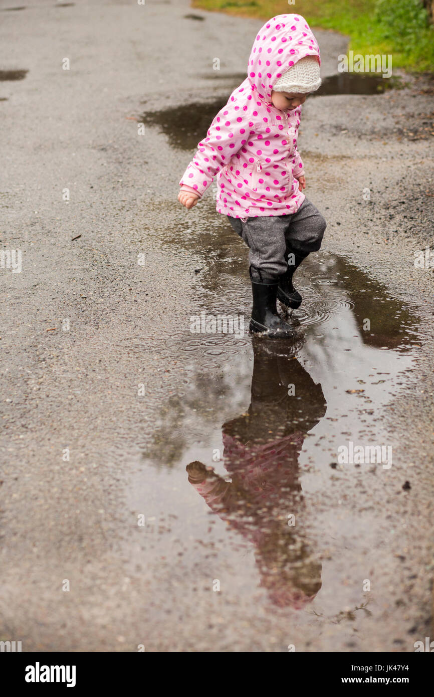 Caucasian girl wearing boots splashing in puddle Stock Photo - Alamy