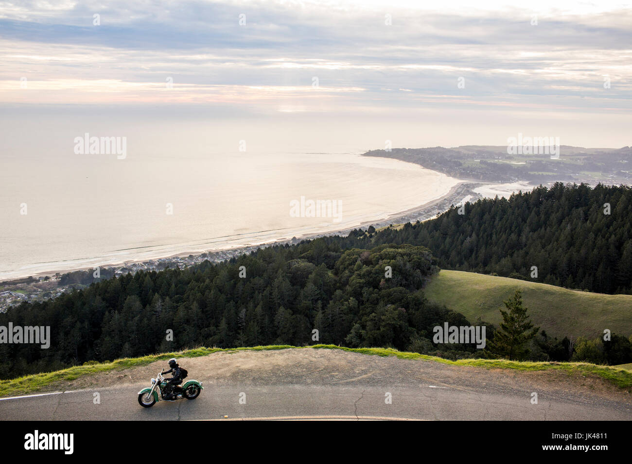 Person riding motorcycle at edge of cliff near ocean Stock Photo - Alamy