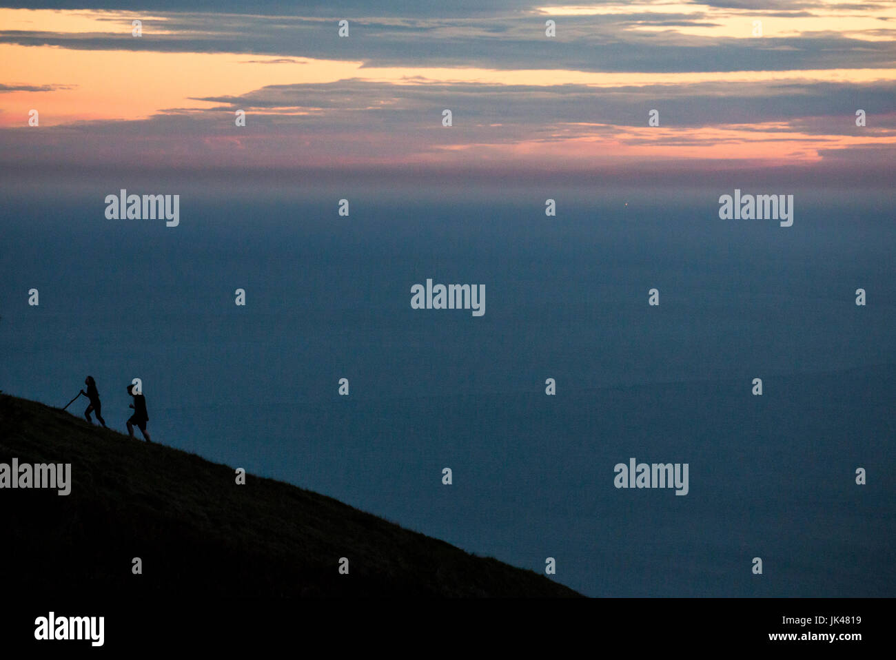 Hikers climbing hill at sunset Stock Photo - Alamy