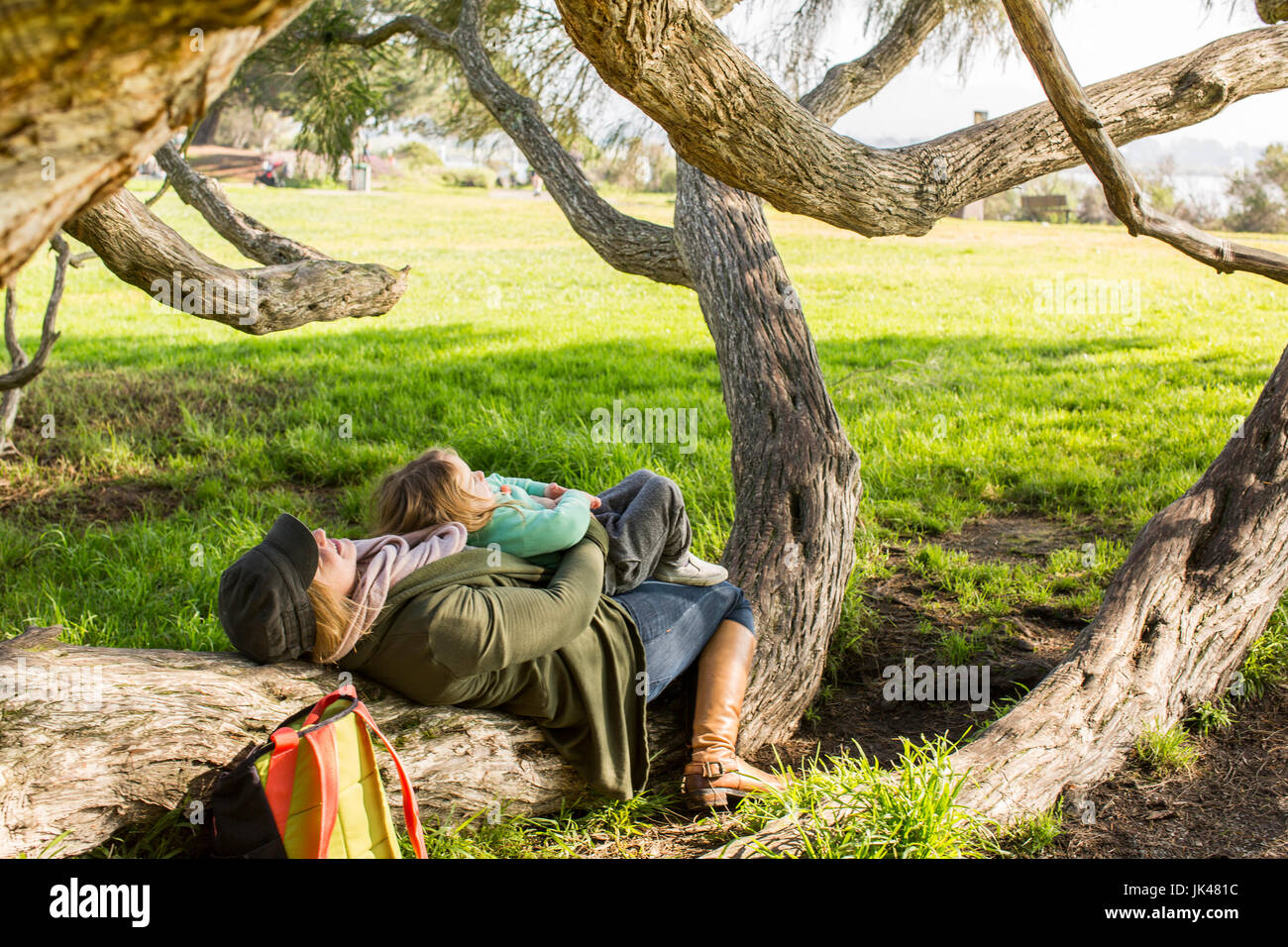 Caucasian mother and daughter laying on tree branch Stock Photo - Alamy