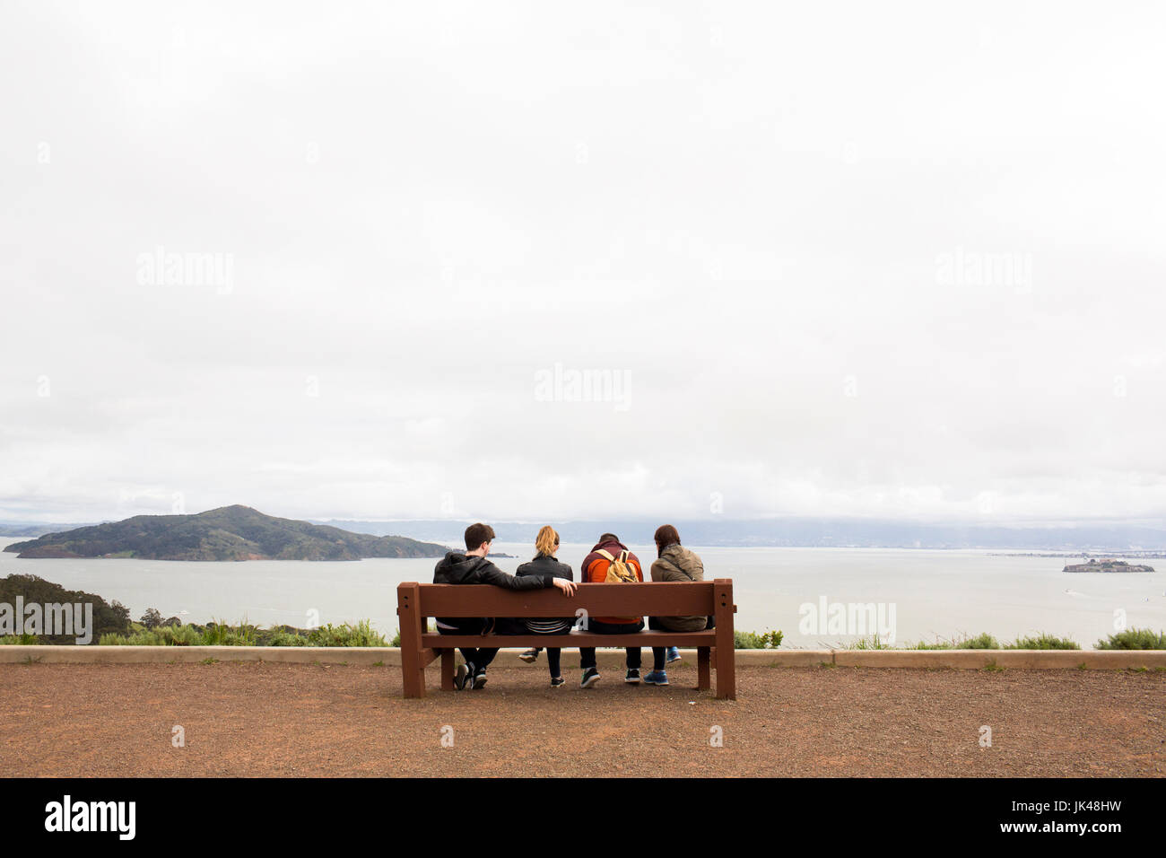 Friends sitting on bench admiring scenic view of ocean Stock Photo - Alamy
