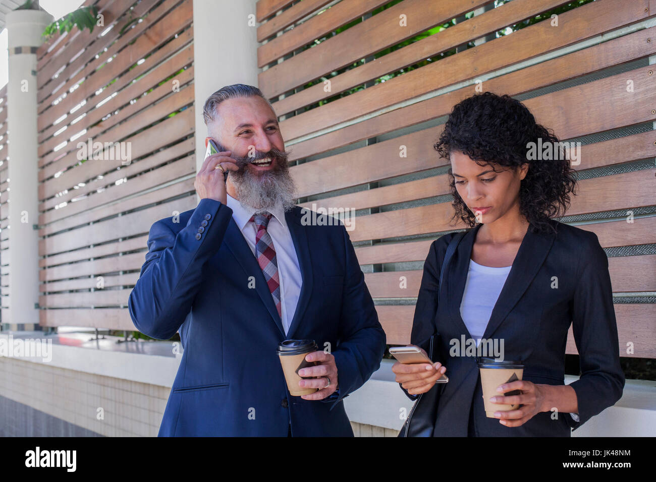 Business people standing outdoors using cell phones Stock Photo - Alamy