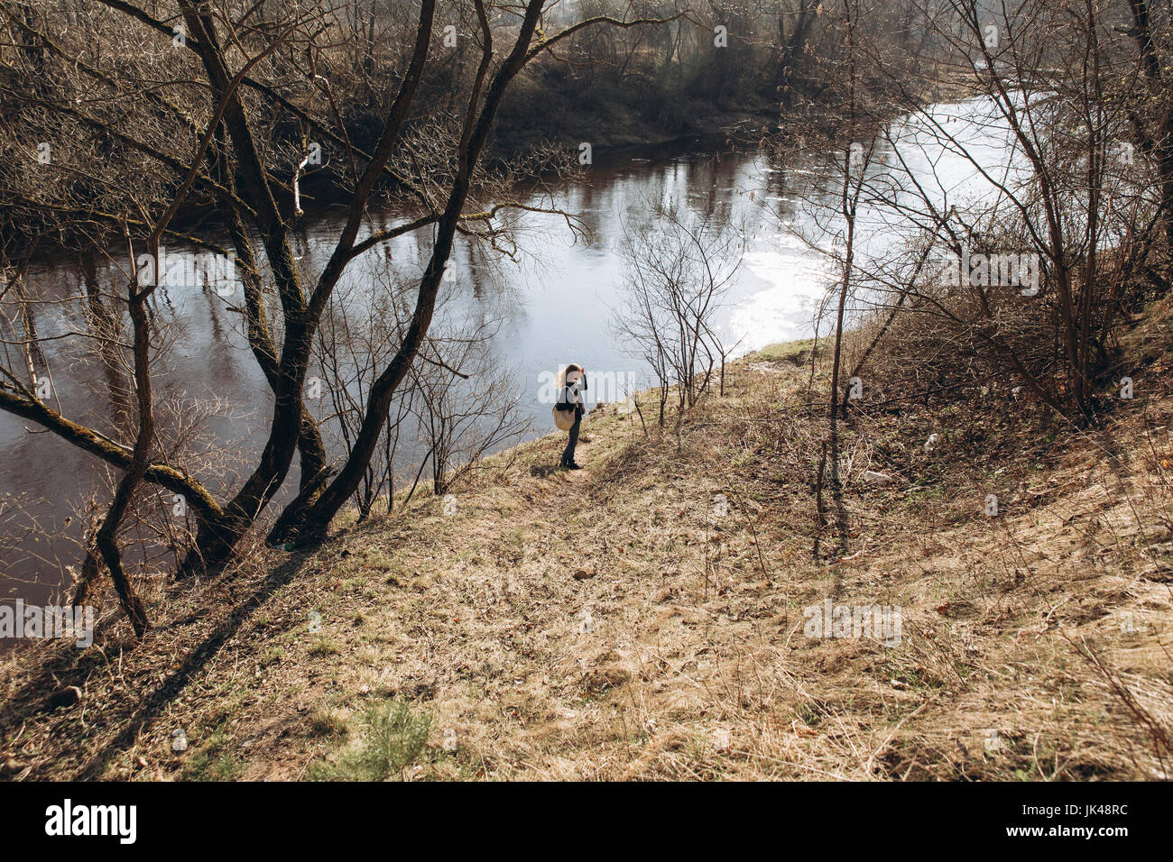 Distant woman standing near river Stock Photo - Alamy