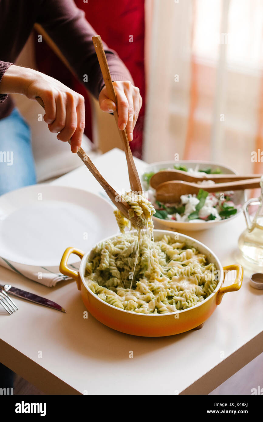 Woman serving pasta with wooden spoons Stock Photo - Alamy