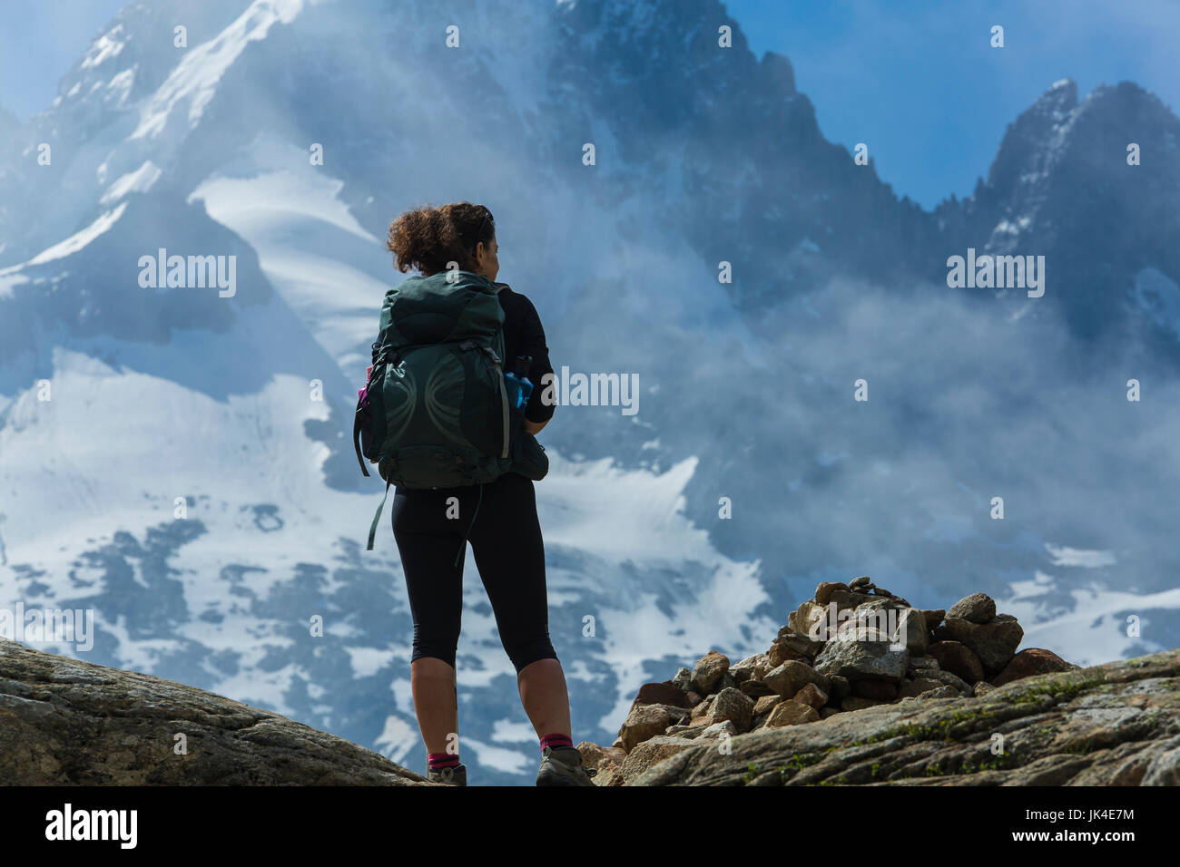Lone female hiker stands on a cliff in the French Alps above Chamonix ...