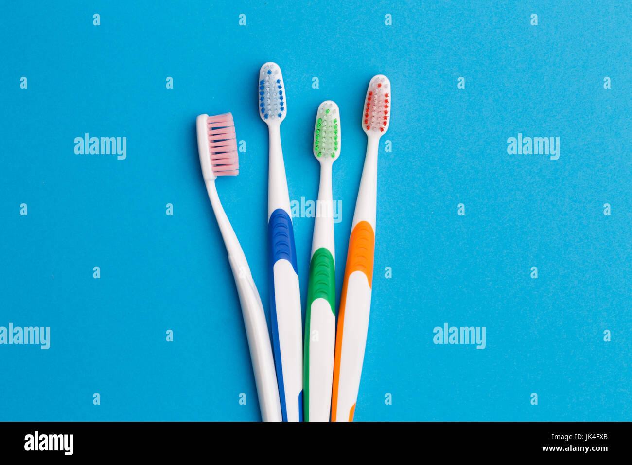 Photo of multi-colored toothbrushes on empty blue background Stock ...