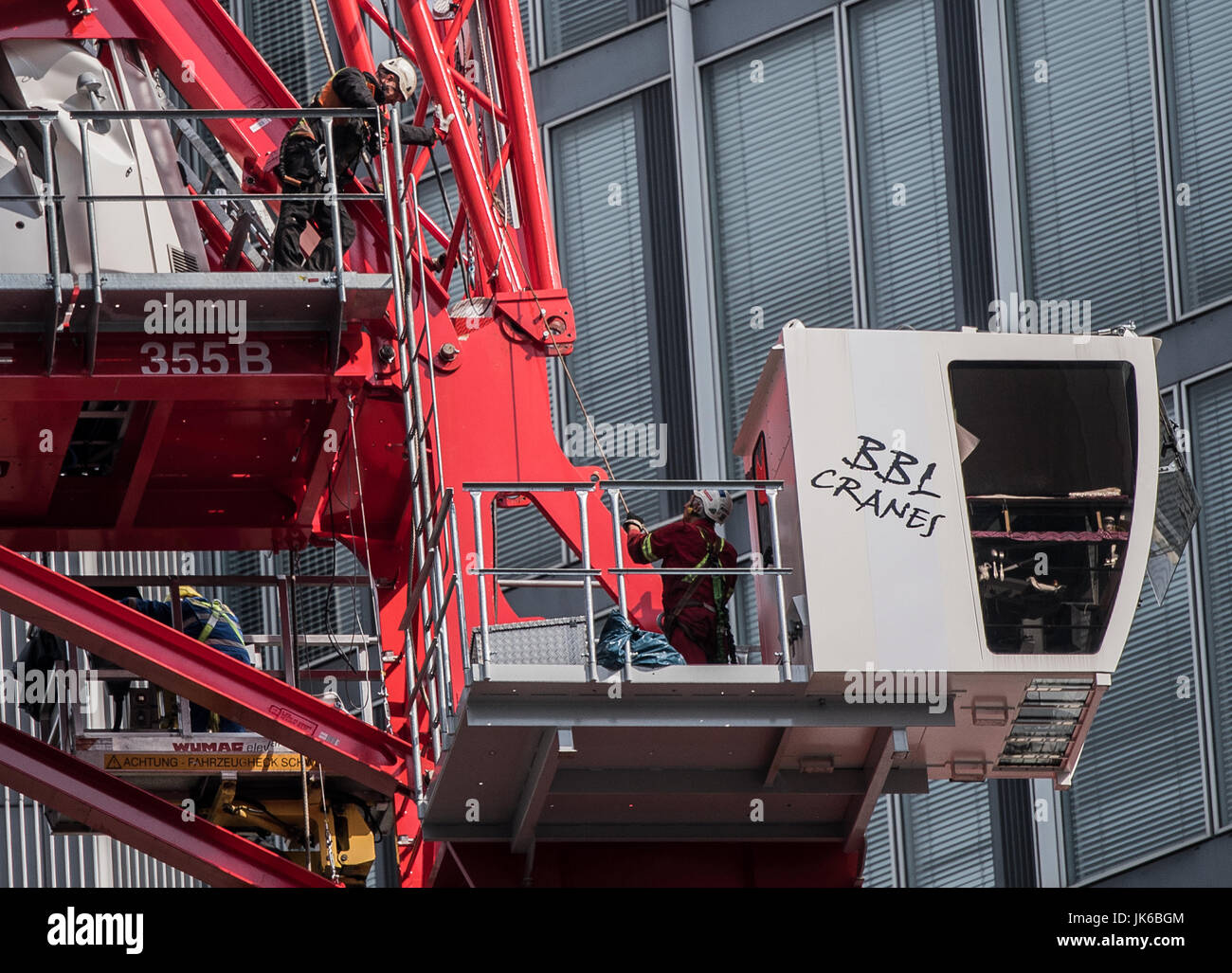 A worker of the recovery team (L) pushes the jib of the damaged crane ...