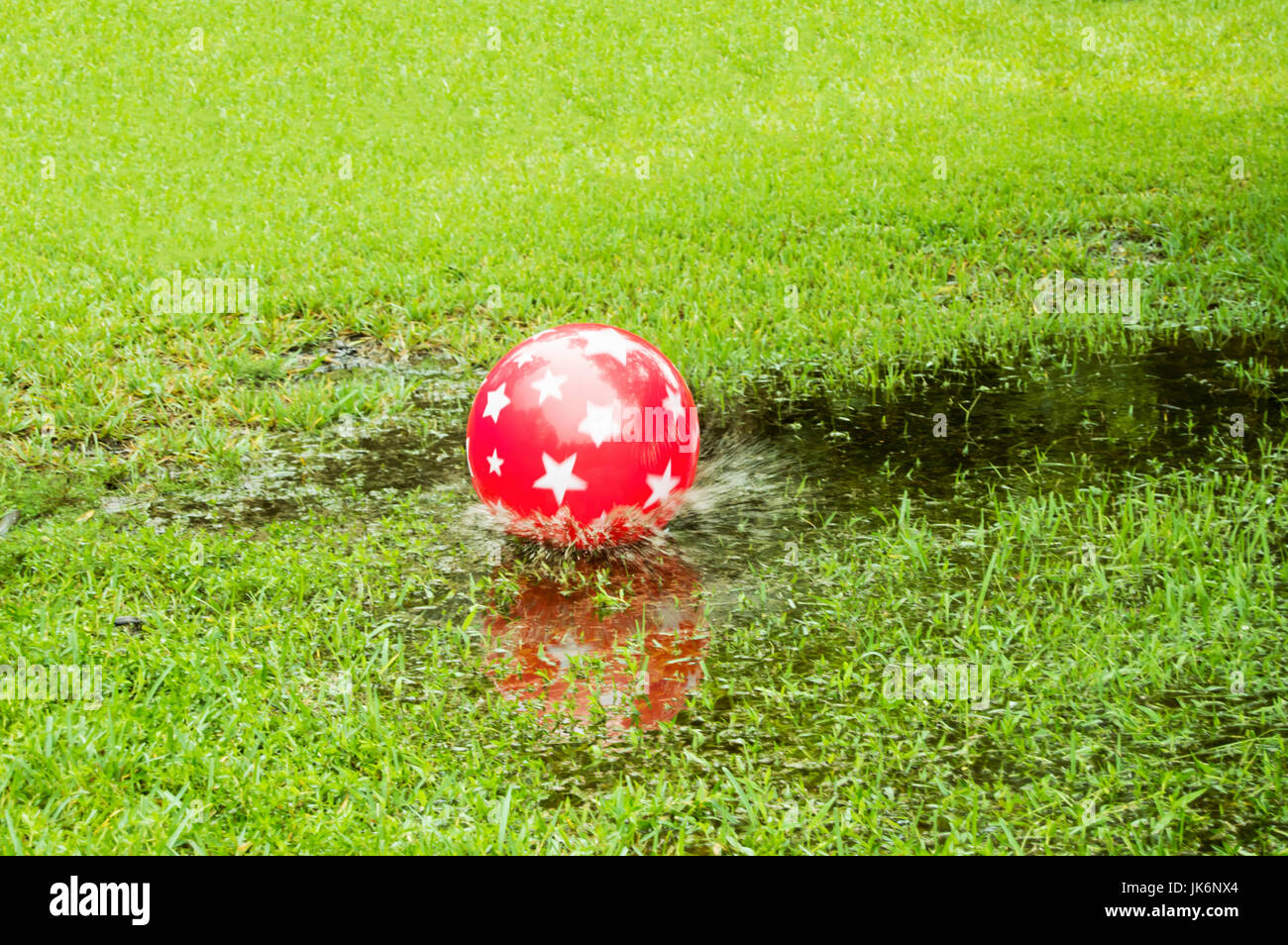 A red ball splashing into a puddle Stock Photo - Alamy