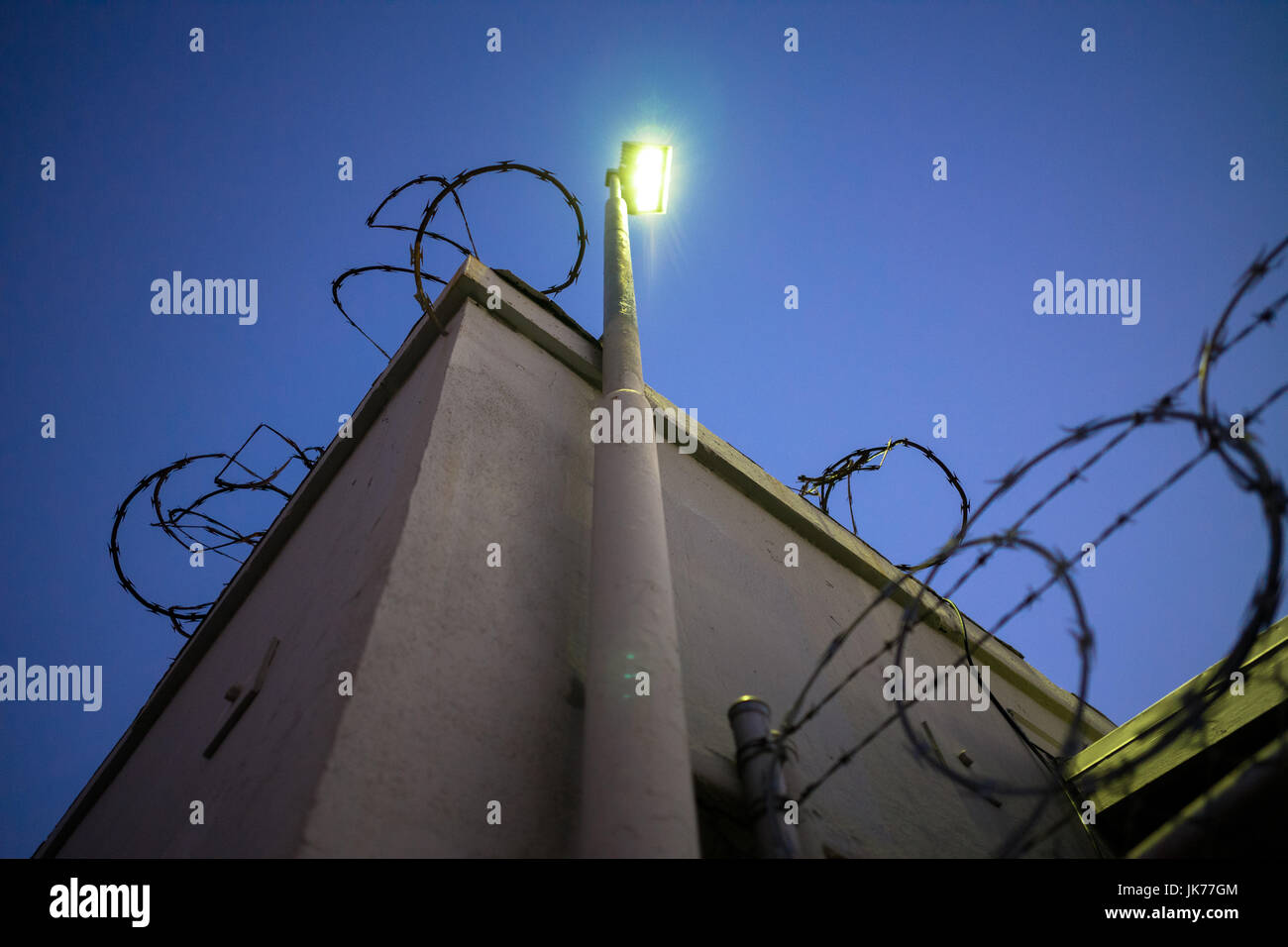 Fence and building protected by barb wire at night Stock Photo - Alamy