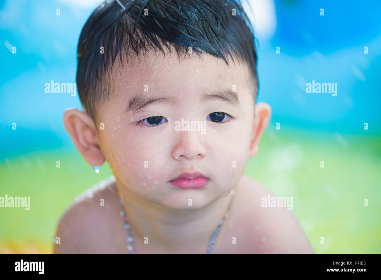 Sad Asian kid playing alone in inflatable baby pool. Boy swim and ...