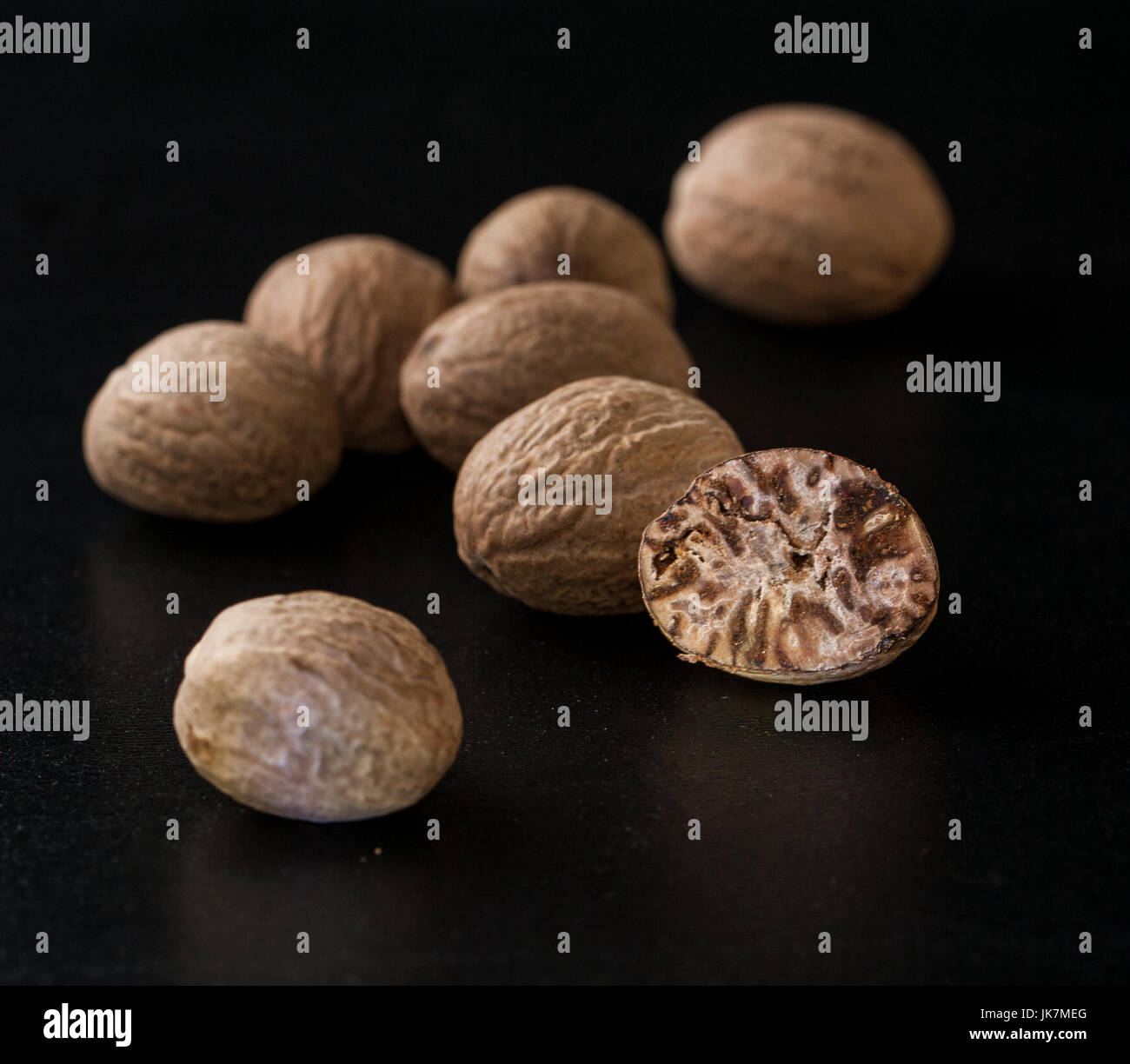 Nutmeg nuts and powder isolated on dark background Stock Photo - Alamy