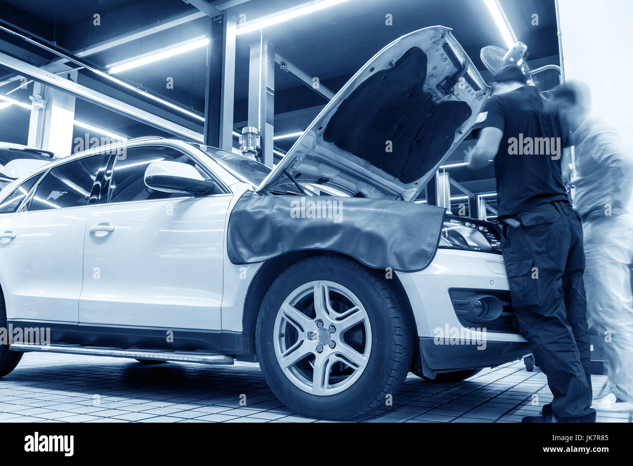The technician is repairing the car, the blue hue Stock Photo - Alamy