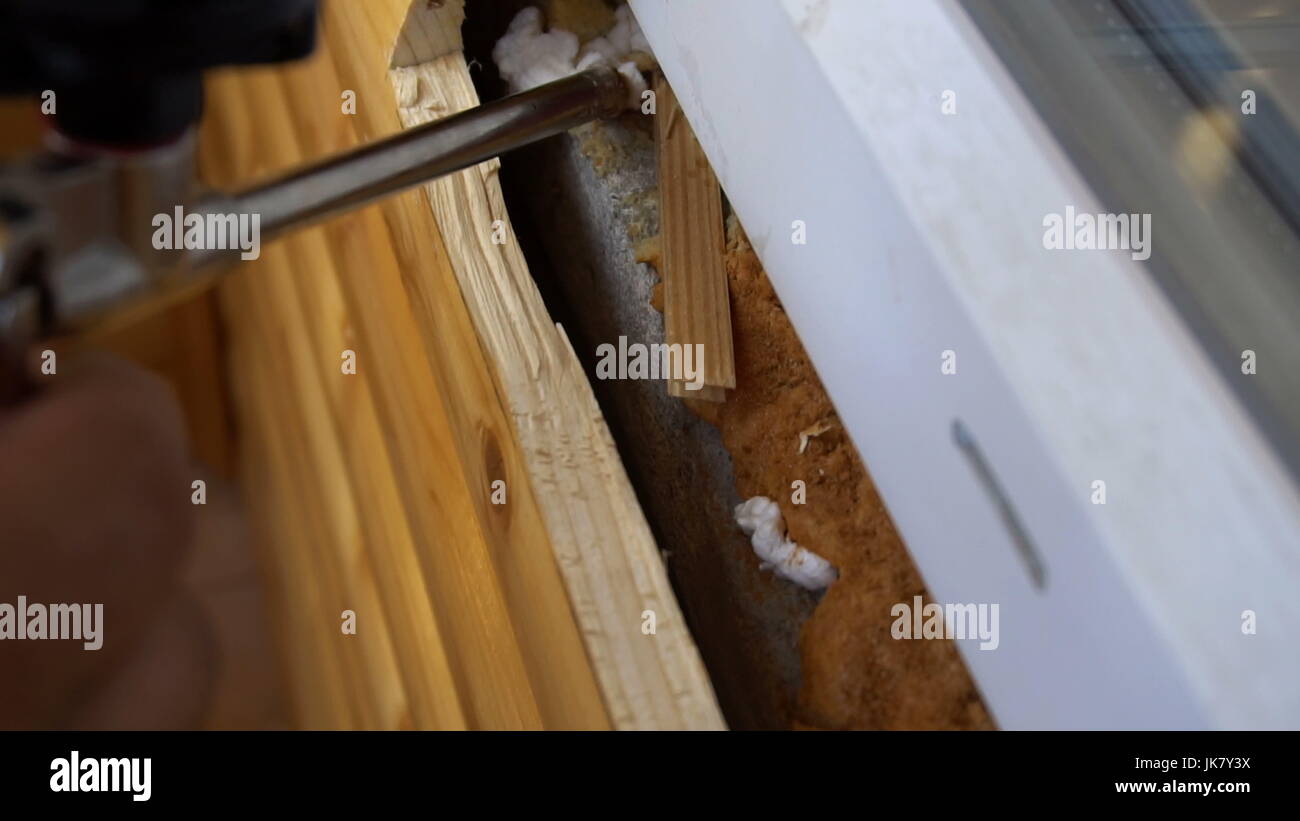 Nozzle of construction gun fills space under window frame by ...