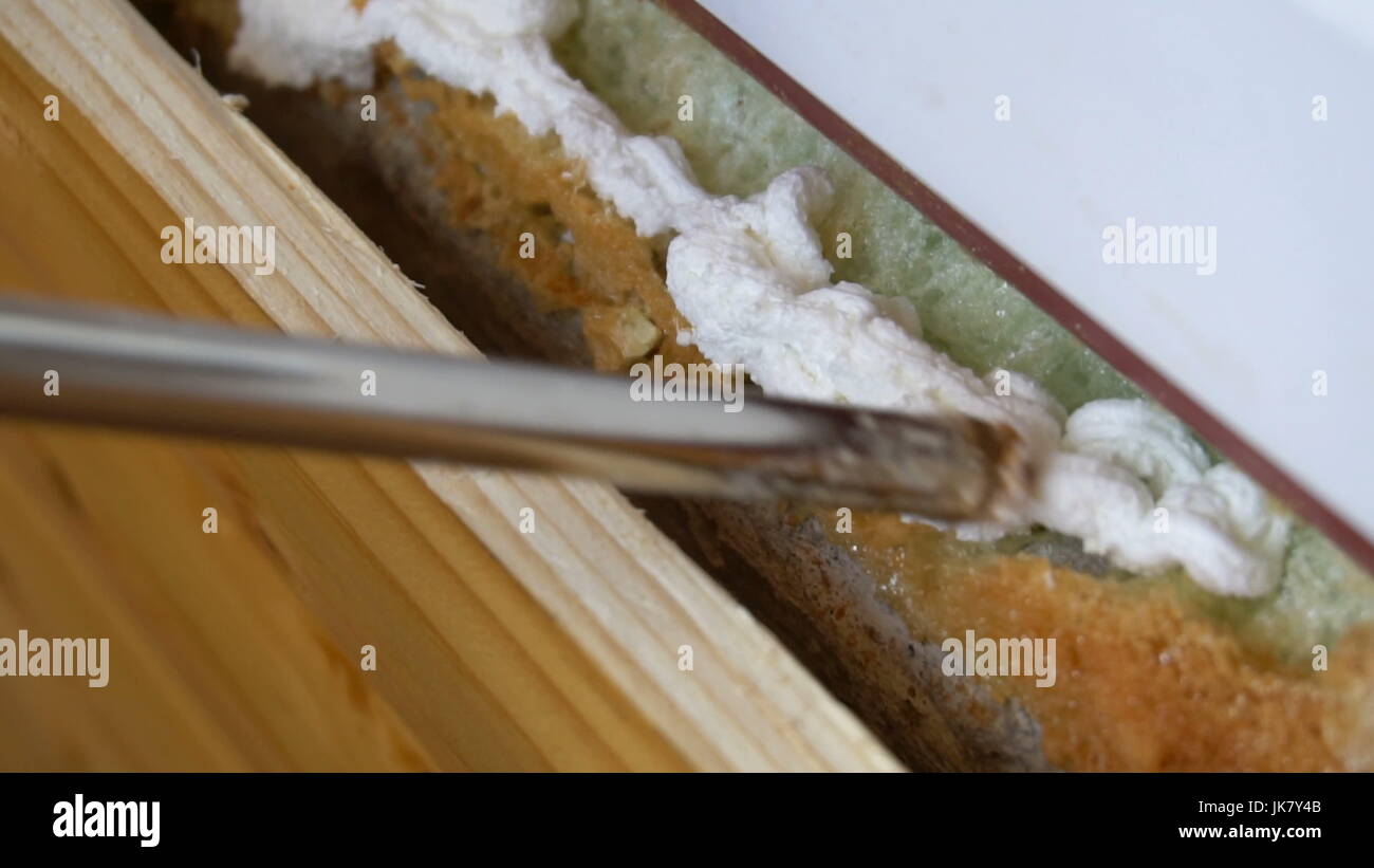 Nozzle of construction gun fills space under window frame by ...