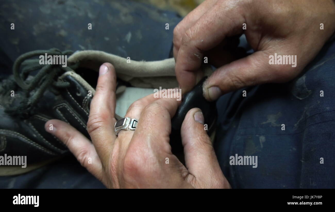 the shoemaker sticks a black leather patch on sneakers Stock Photo - Alamy