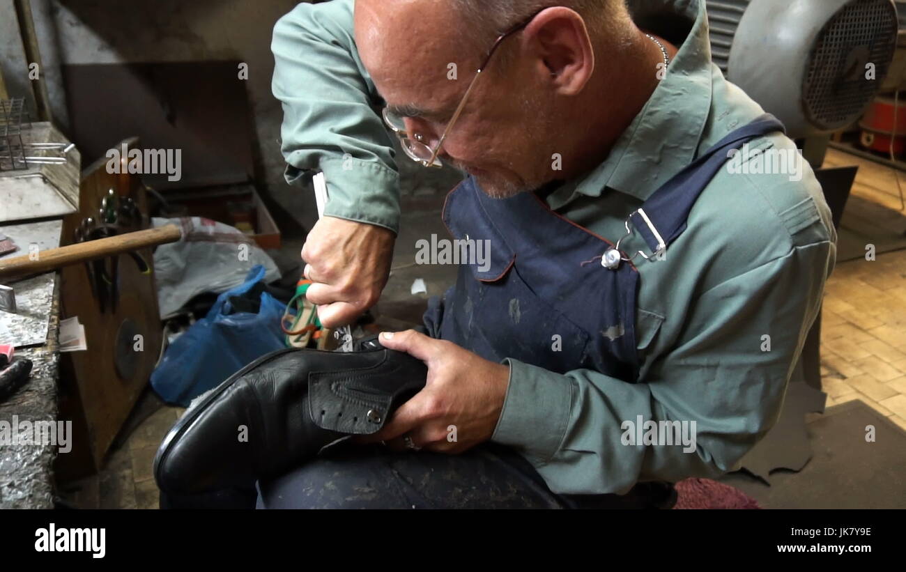 Shoemaker repairing a shoe in workshop 4k. cut the taps on the shoes ...
