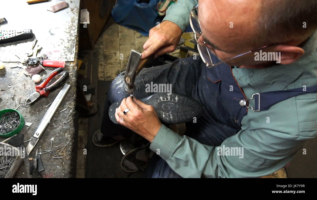 Shoemaker repairing a shoe in workshop 4k. nail the heel cap to the ...