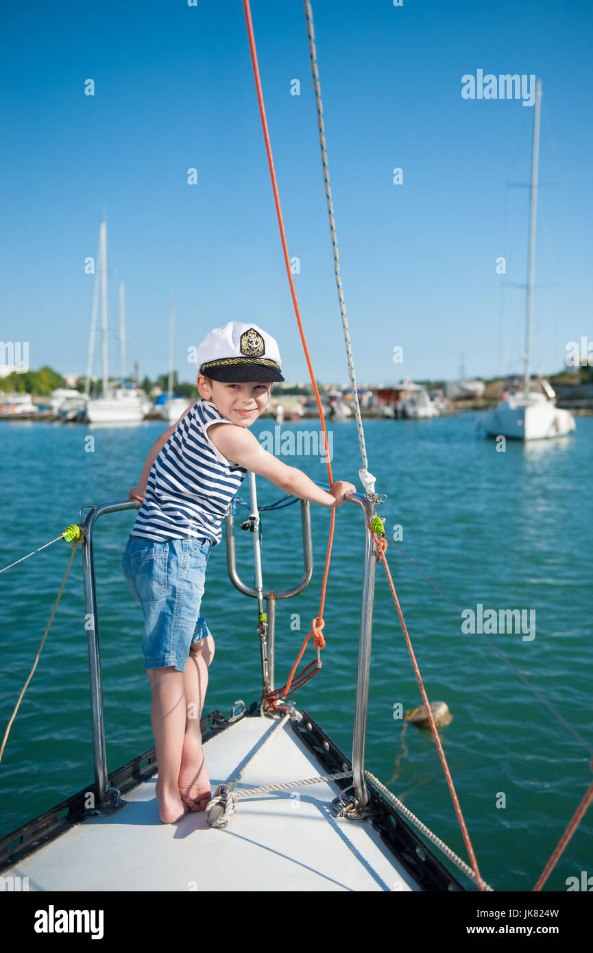 smiling little boy captain aboard luxury boat during the ocean cruise ...