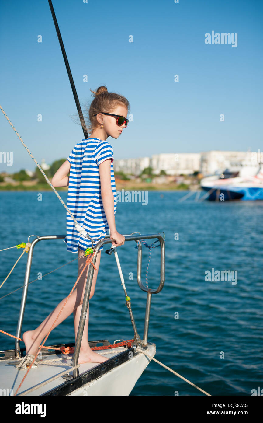 elegant slim little girl in sunglasses aboard luxury yacht during ocean ...