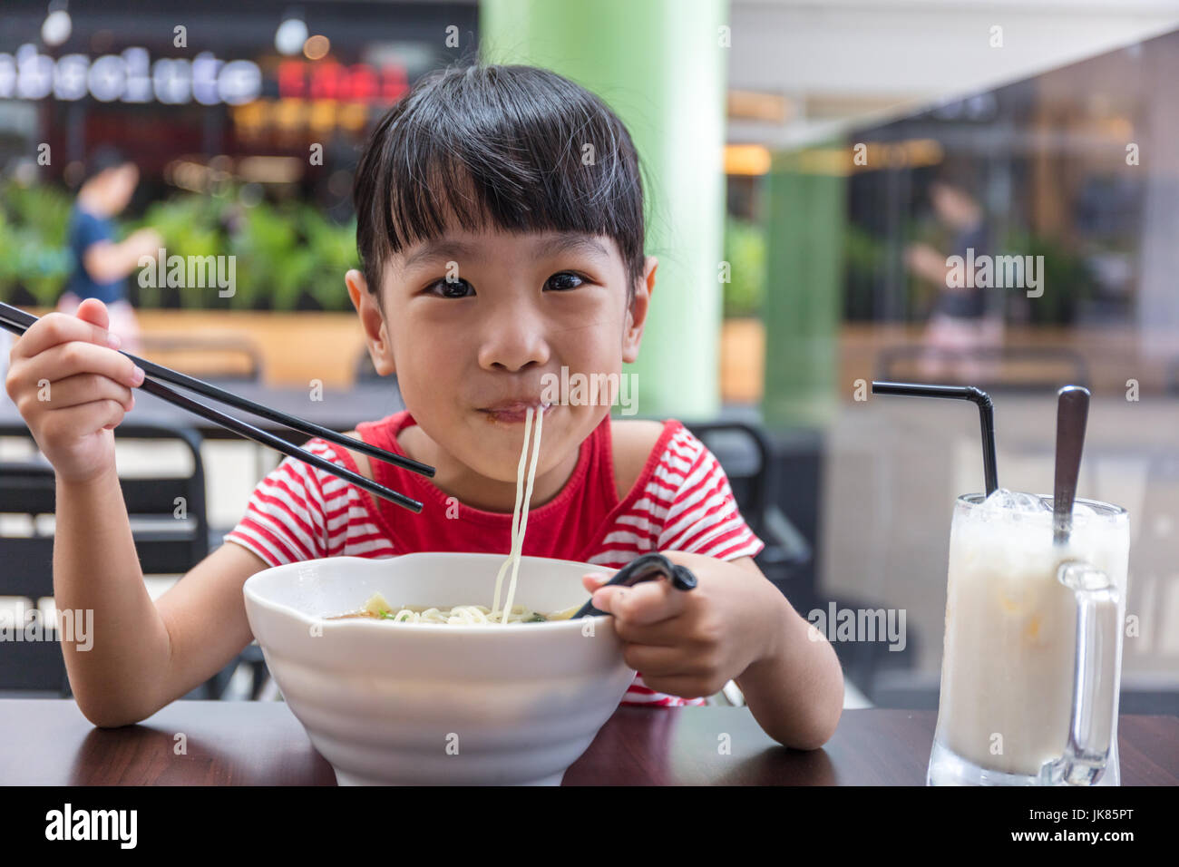 Asian little Chinese girl eating noodles soup in outdoor cafe Stock ...