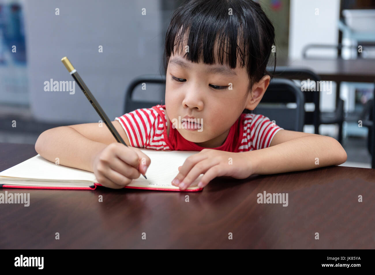 Asian Chinese little girl doing homework at outdoor cafe Stock Photo ...
