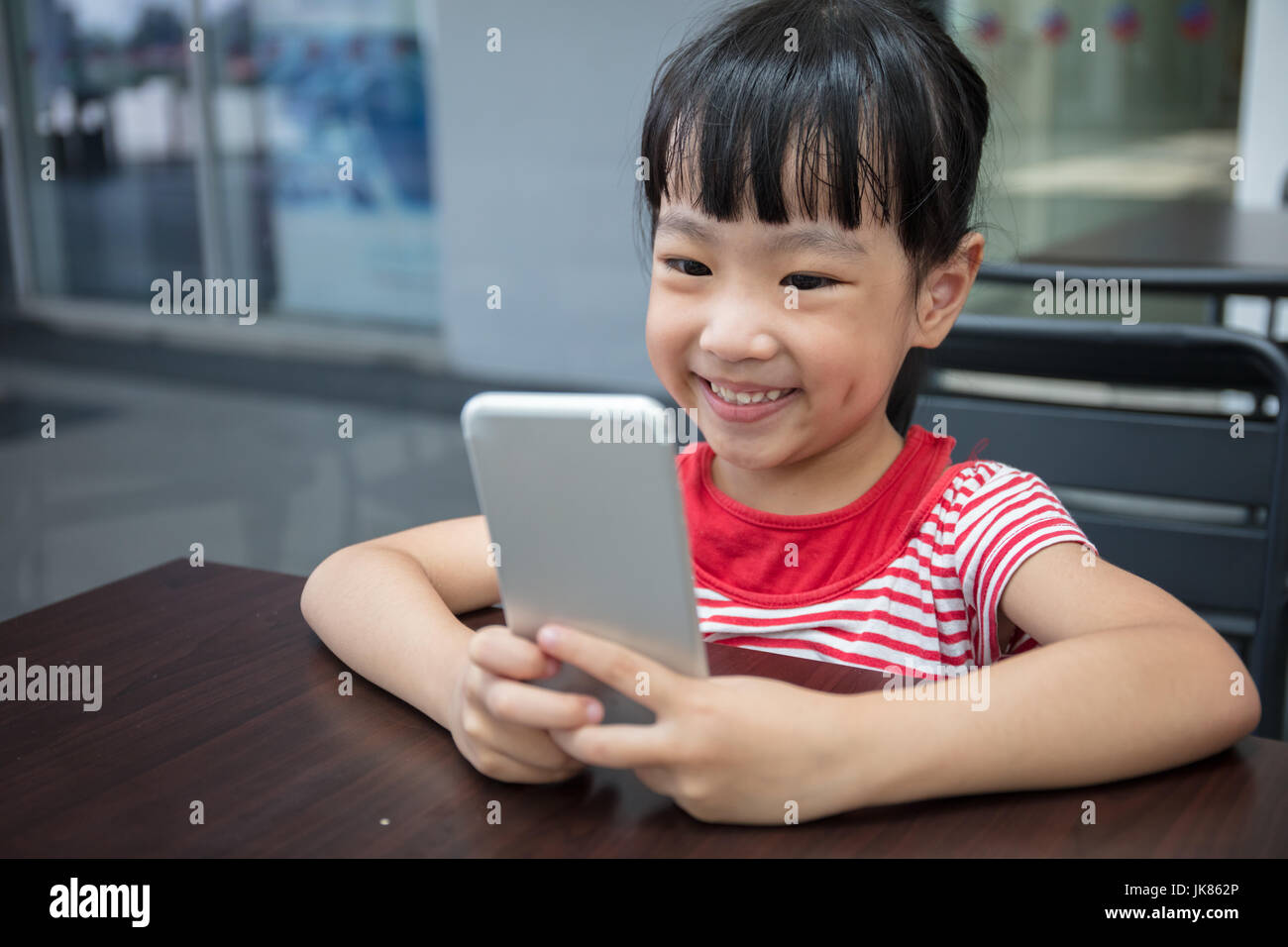 Asian Chinese little girl playing smartphone at outdoor cafe Stock ...