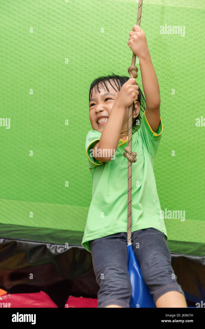 Asian Chinese little girl riding on a rope in the gym class Stock Photo ...
