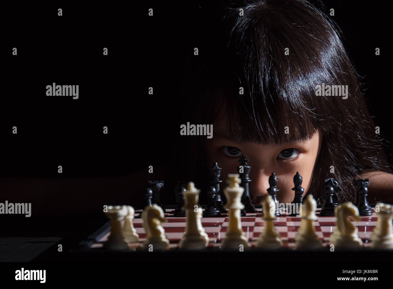 Asian Little Chinese girl playing chess in isolated black background ...