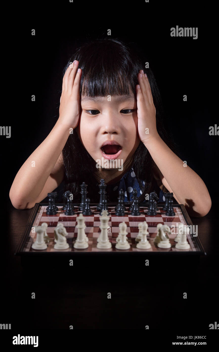 Asian Little Chinese girl playing chess in isolated black background ...