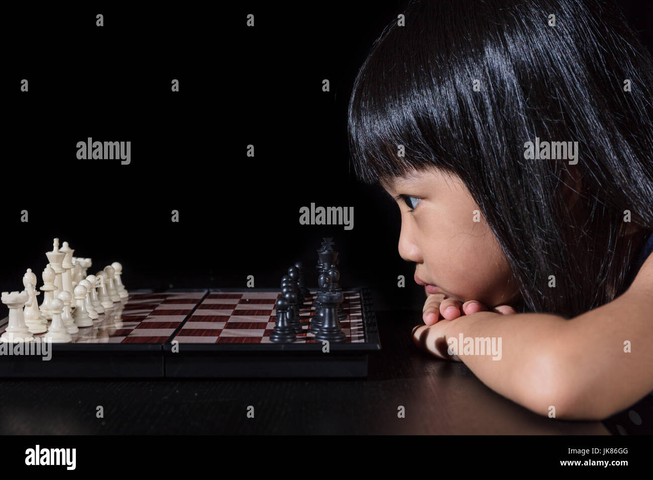Asian Little Chinese girl playing chess in isolated black background ...