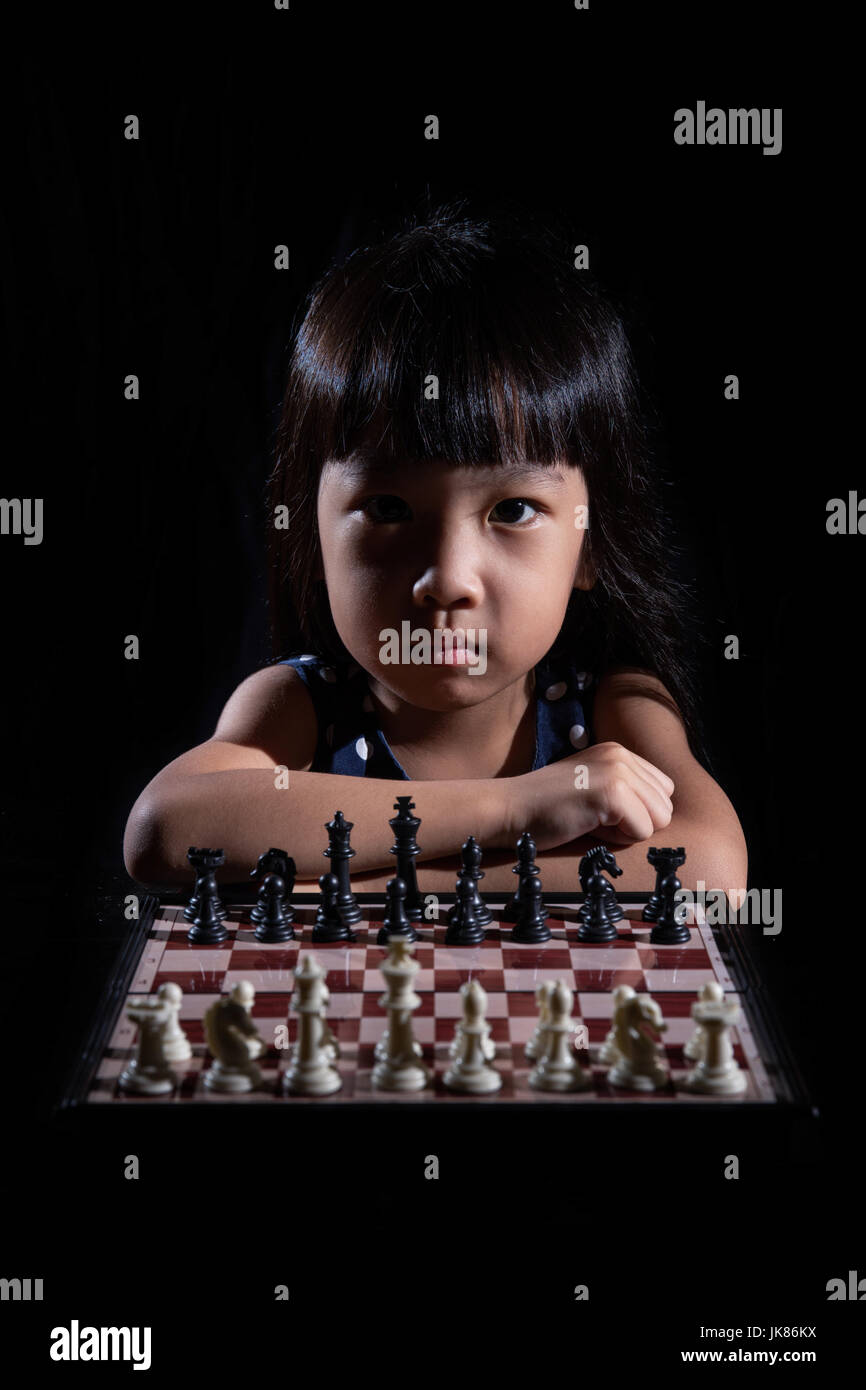 Asian Little Chinese girl playing chess in isolated black background ...