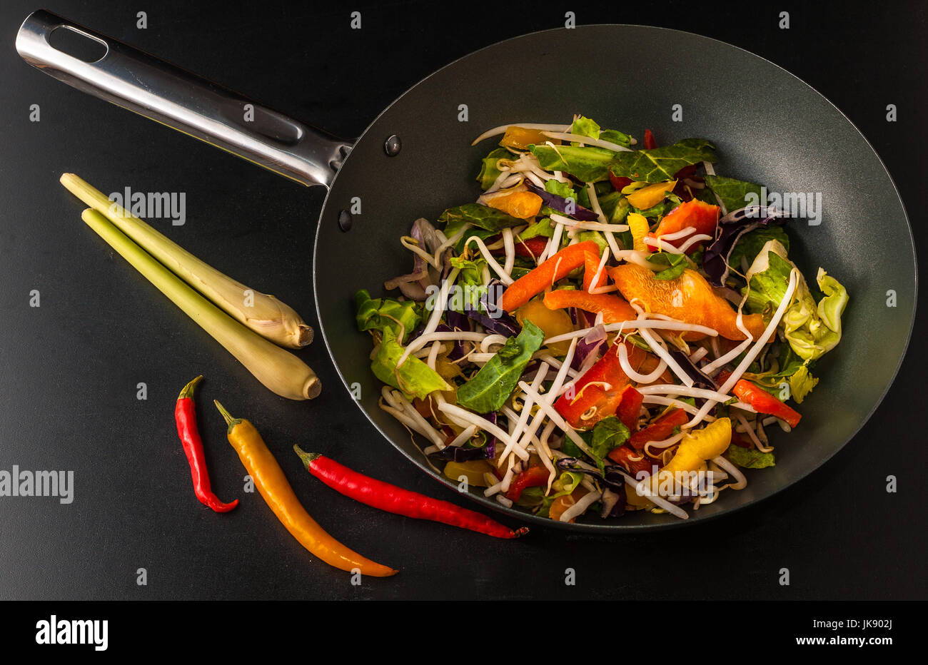 Asian cuisine set: black wok, chopsticks, stir fry vegetables and ...