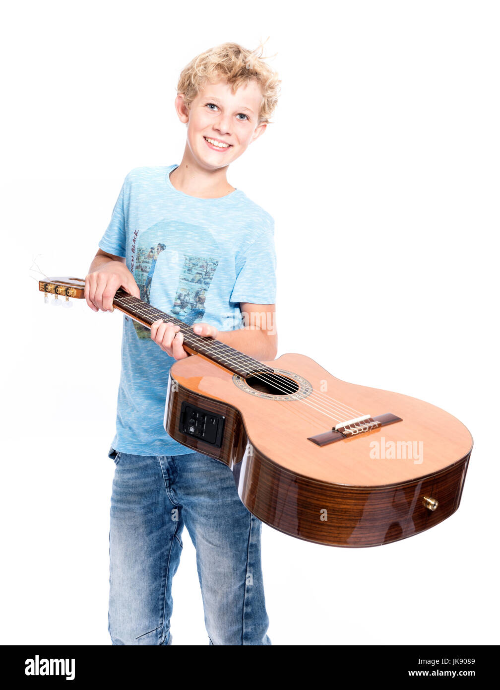 blond teen boy in bue with guitar in studio against white background ...