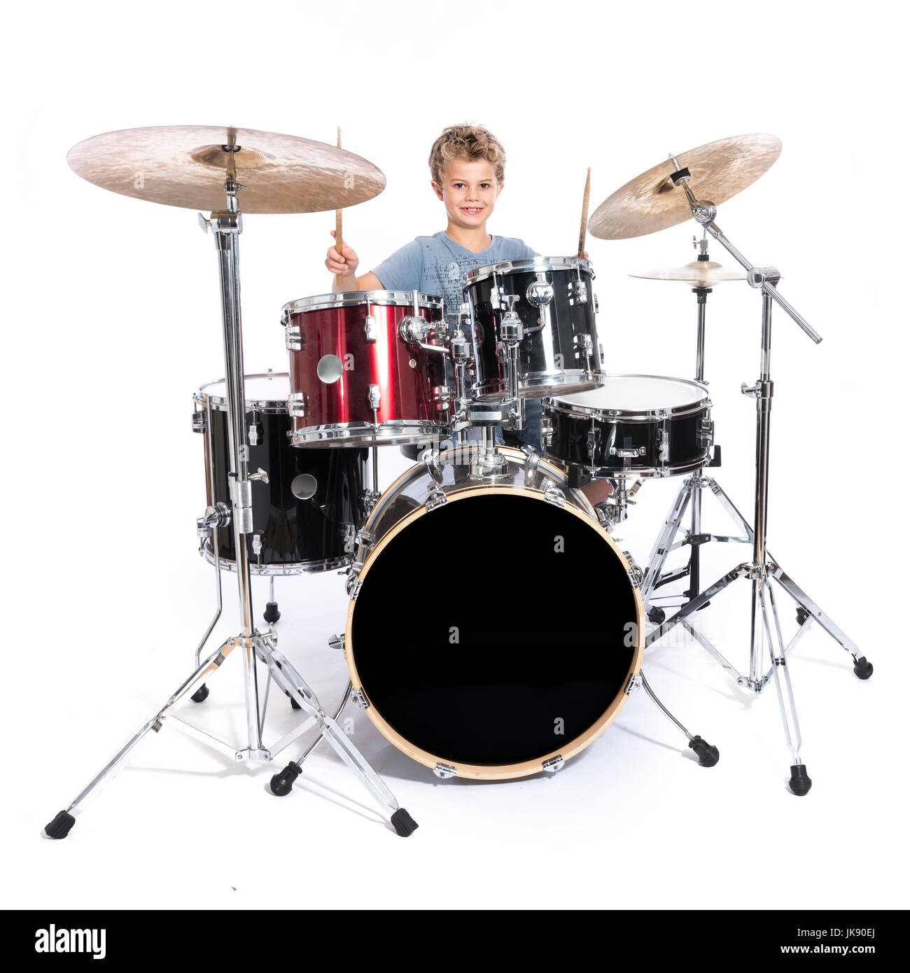 young blond caucasian boy plays drums in studio against white ...