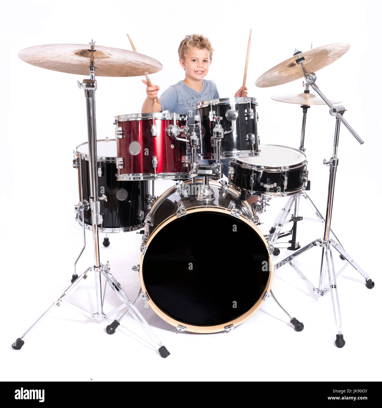 young blond caucasian boy plays drums in studio against white ...