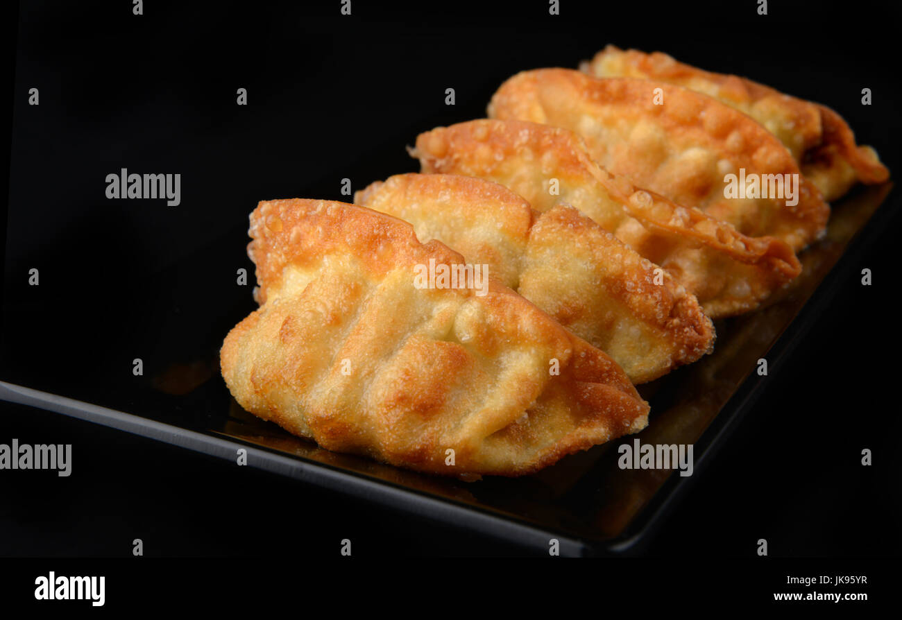 Deep fried gyoza crispy and golden colour set on black plate with ...