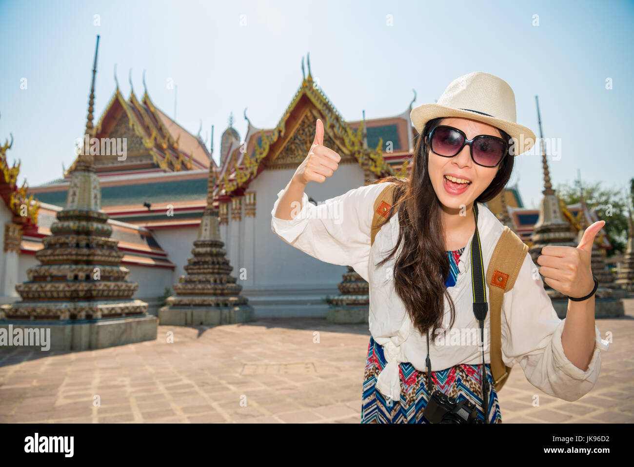 Happy tourist girl at wat pho of Thailand doing thumbs up hand sign ...
