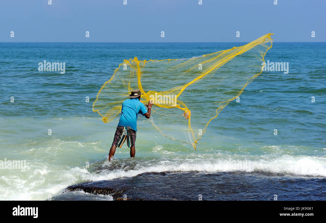 Fisherman throwing yellow fishing net Stock Photo - Alamy