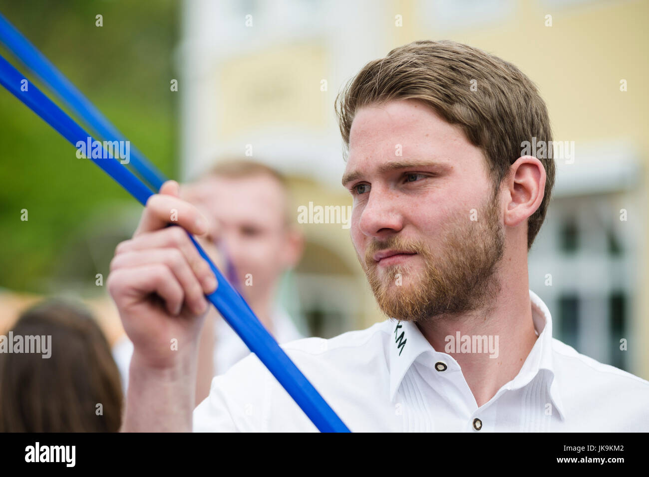 Head of young Bavarian man in white shirt holding blue ribbon while ...