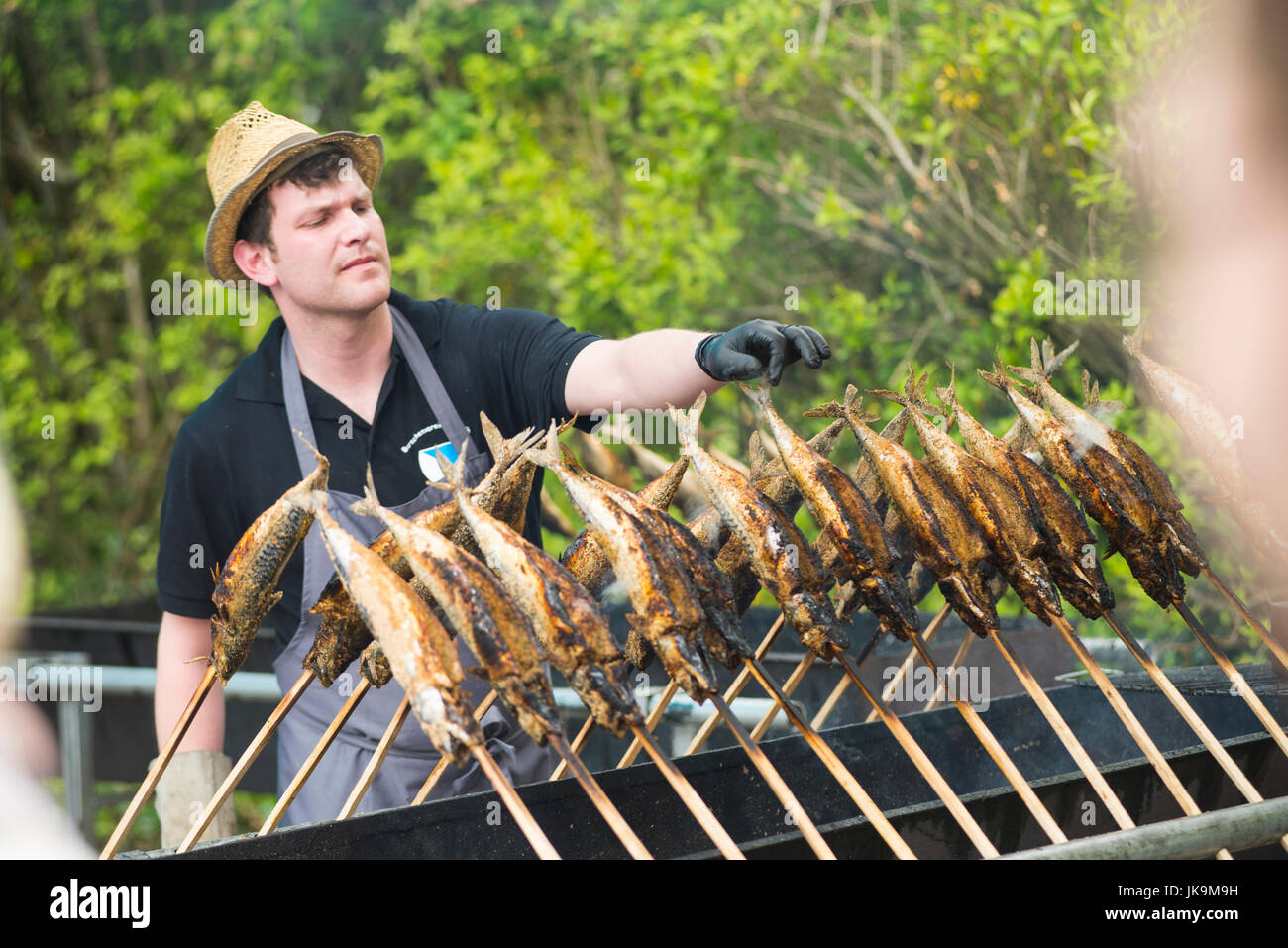 Young man touching fish on a stick like trout,char or whitefisch ...
