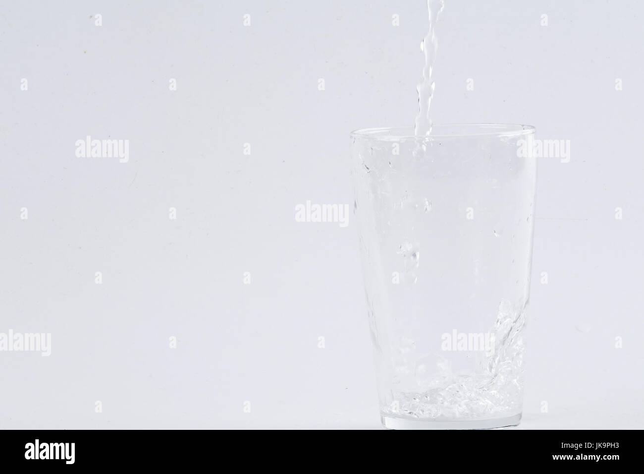 Water pouring into clear glass over white background Stock Photo - Alamy