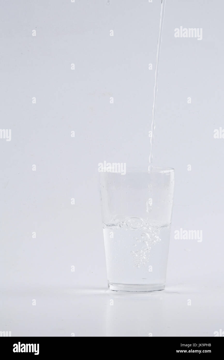 Water pouring into clear glass over white background Stock Photo - Alamy