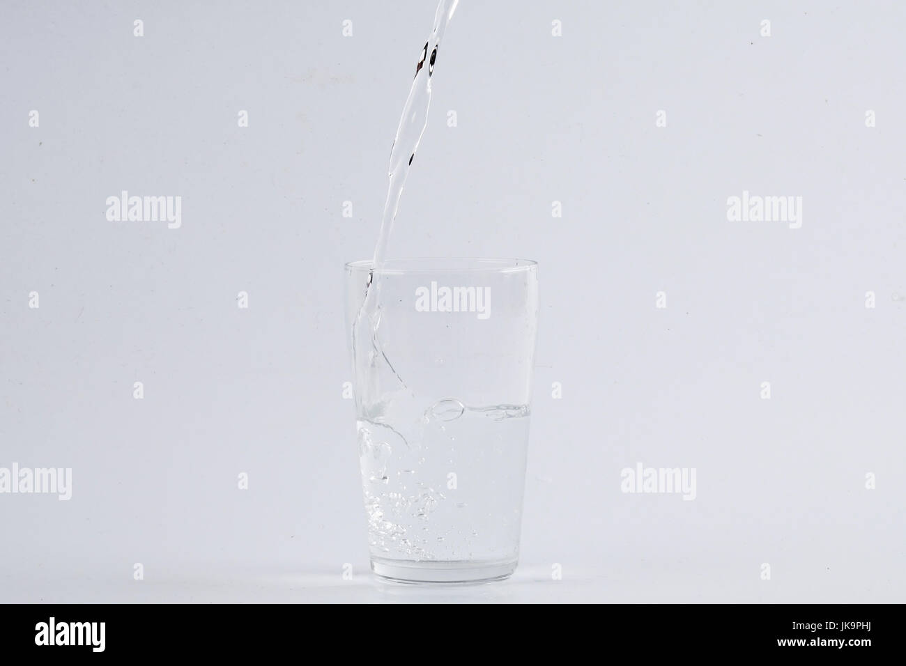 Water pouring into clear glass over white background Stock Photo - Alamy
