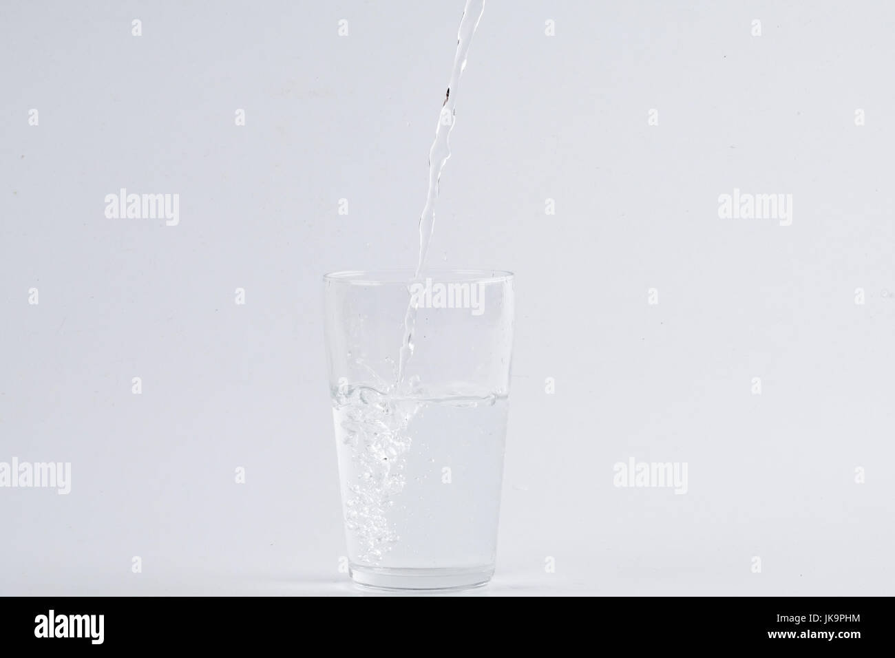 Water pouring into clear glass over white background Stock Photo - Alamy