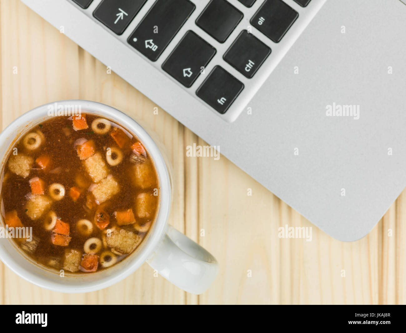 Cup of Instant Minestrone Soup And A Laptop Computer Against a Light ...