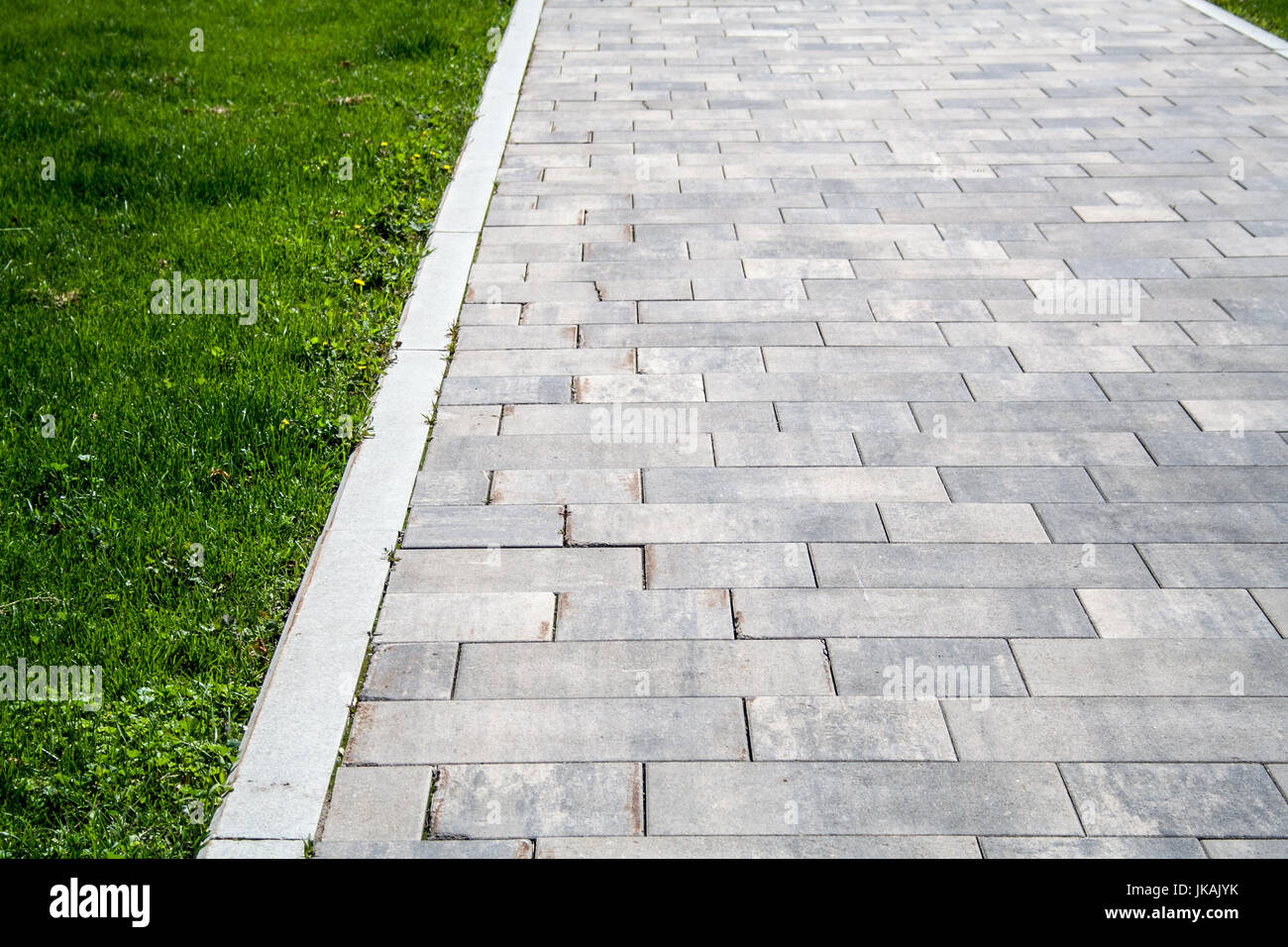 Gray stone tiled sidewalk with grass. background, nature Stock Photo ...